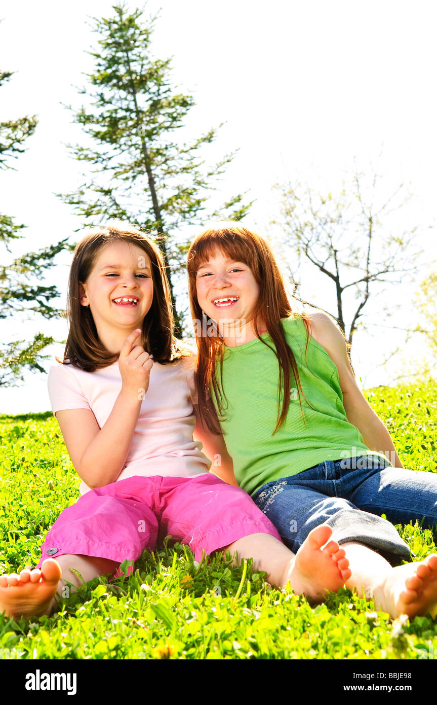 Portrait of happy girls sitting on grass Stock Photo - Alamy