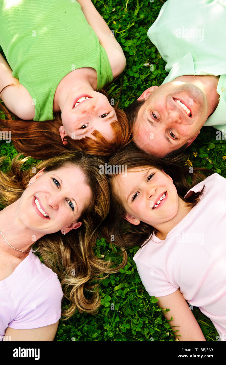 Portrait of happy family laying on grass looking up heads together ...