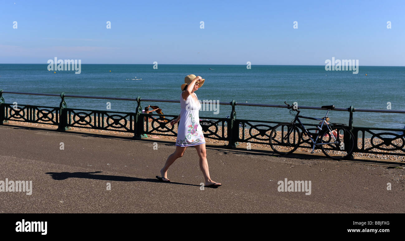 Lady in sunhat walking along Hove seafront promenade Stock Photo - Alamy