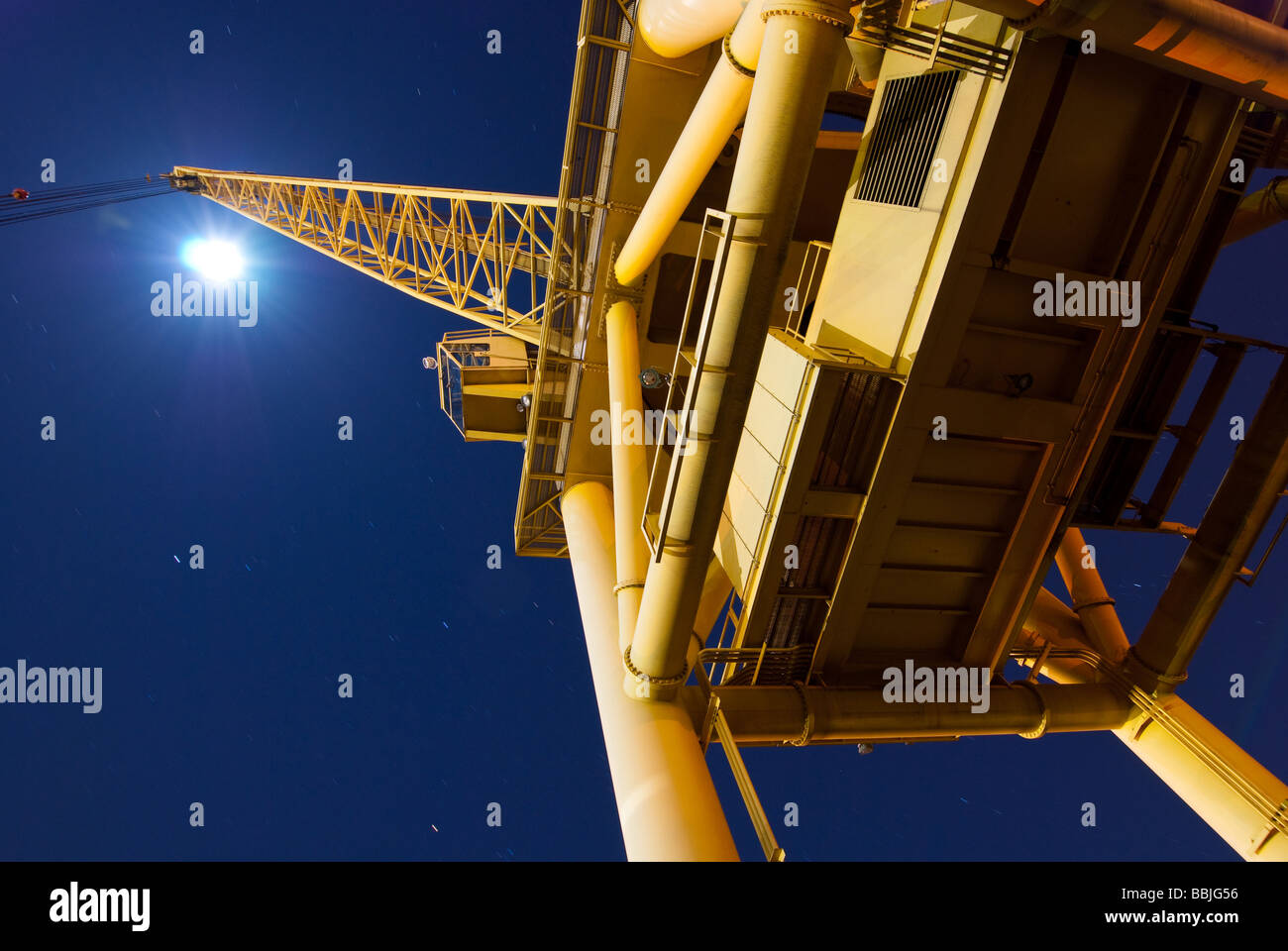 Night shot of a giant industrial crane with moon in the background ...