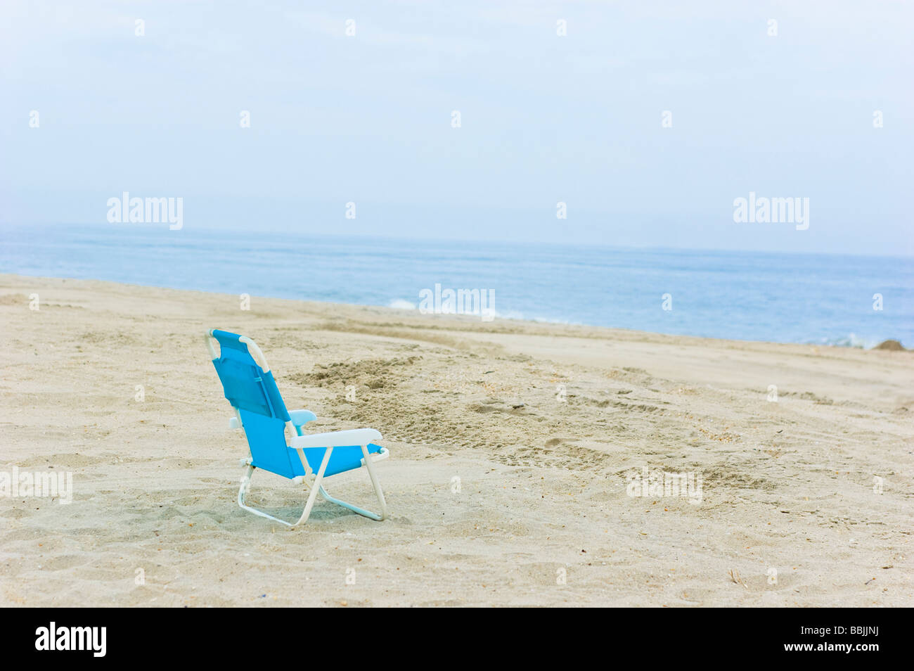 Blue beach chair overlooking empty ocean on beach Stock Photo - Alamy