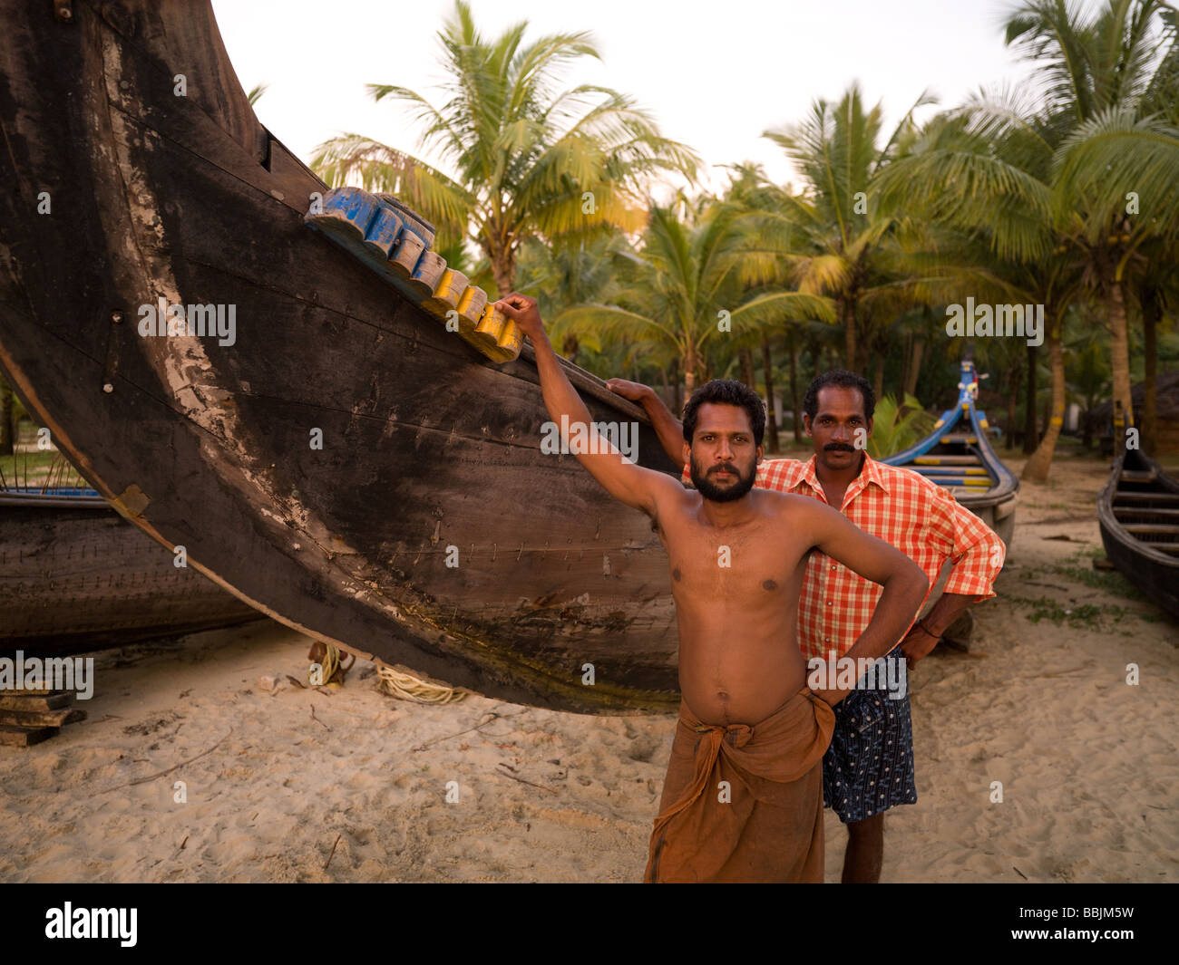 Two men standing beside hanging canoe in India Stock Photo - Alamy