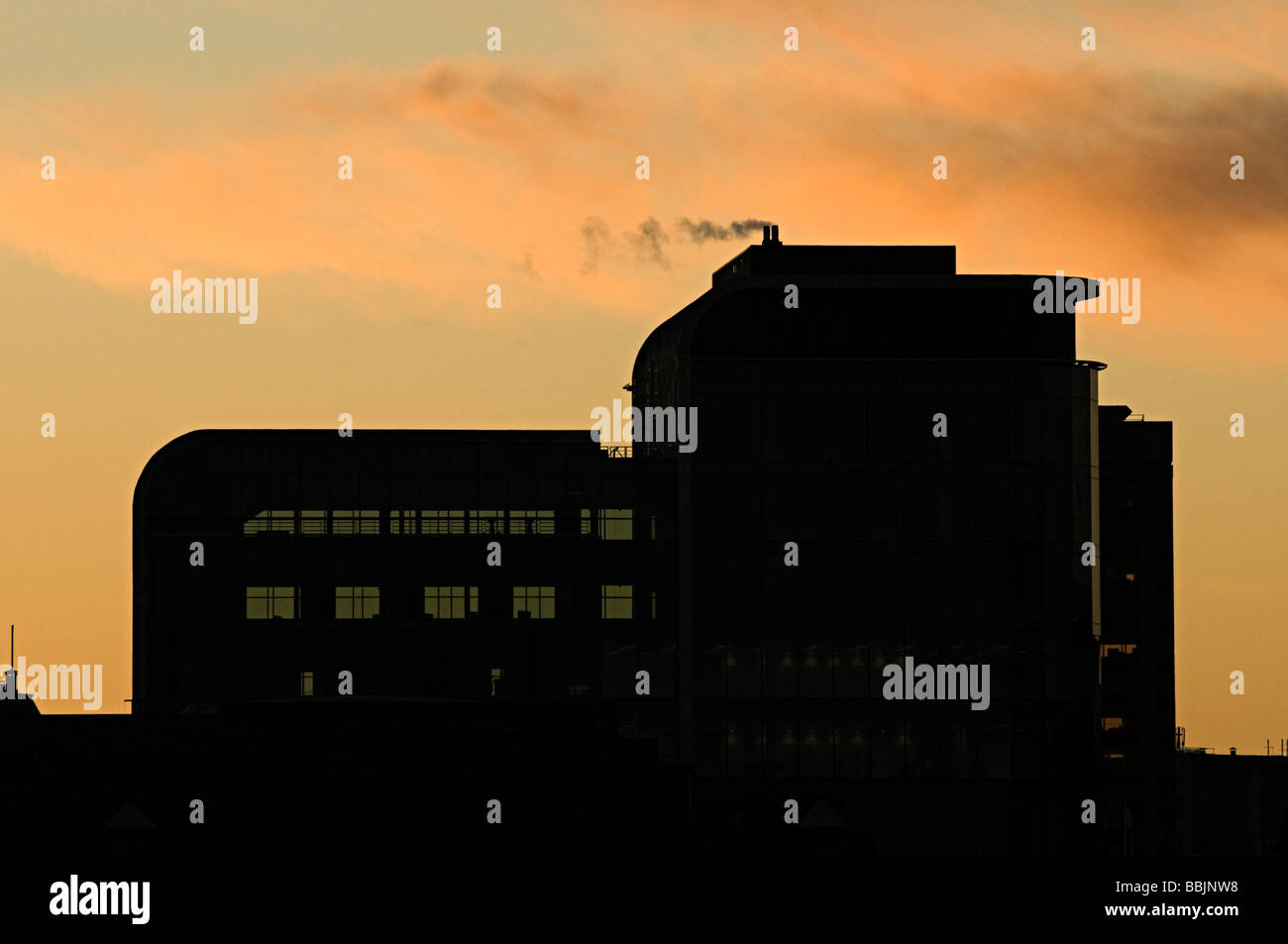 a building at sunset with smoke coming out of the top from its chimney ...