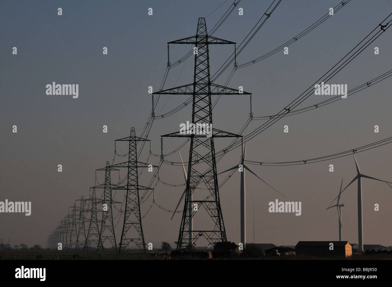 Pylons from the Dungeness Nuclear Power Station pass a wind farm on the ...