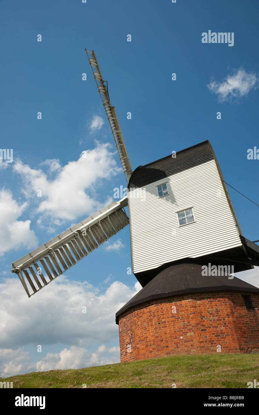 Old wood windmill on red brick tower against blue sky with clouds ...