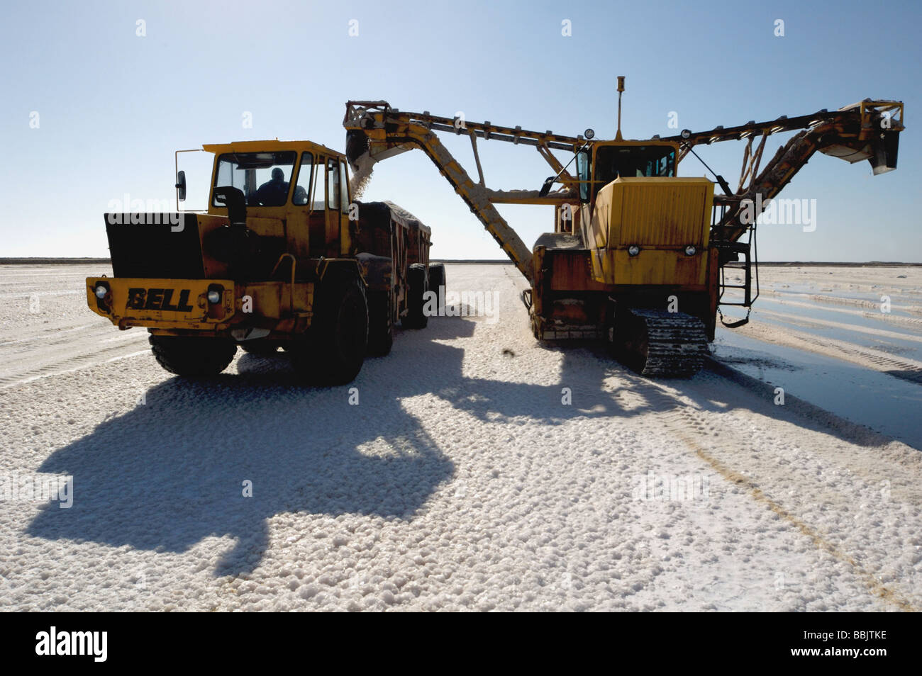 Machine harvesting of salt from sea water evaporation pans Stock Photo ...