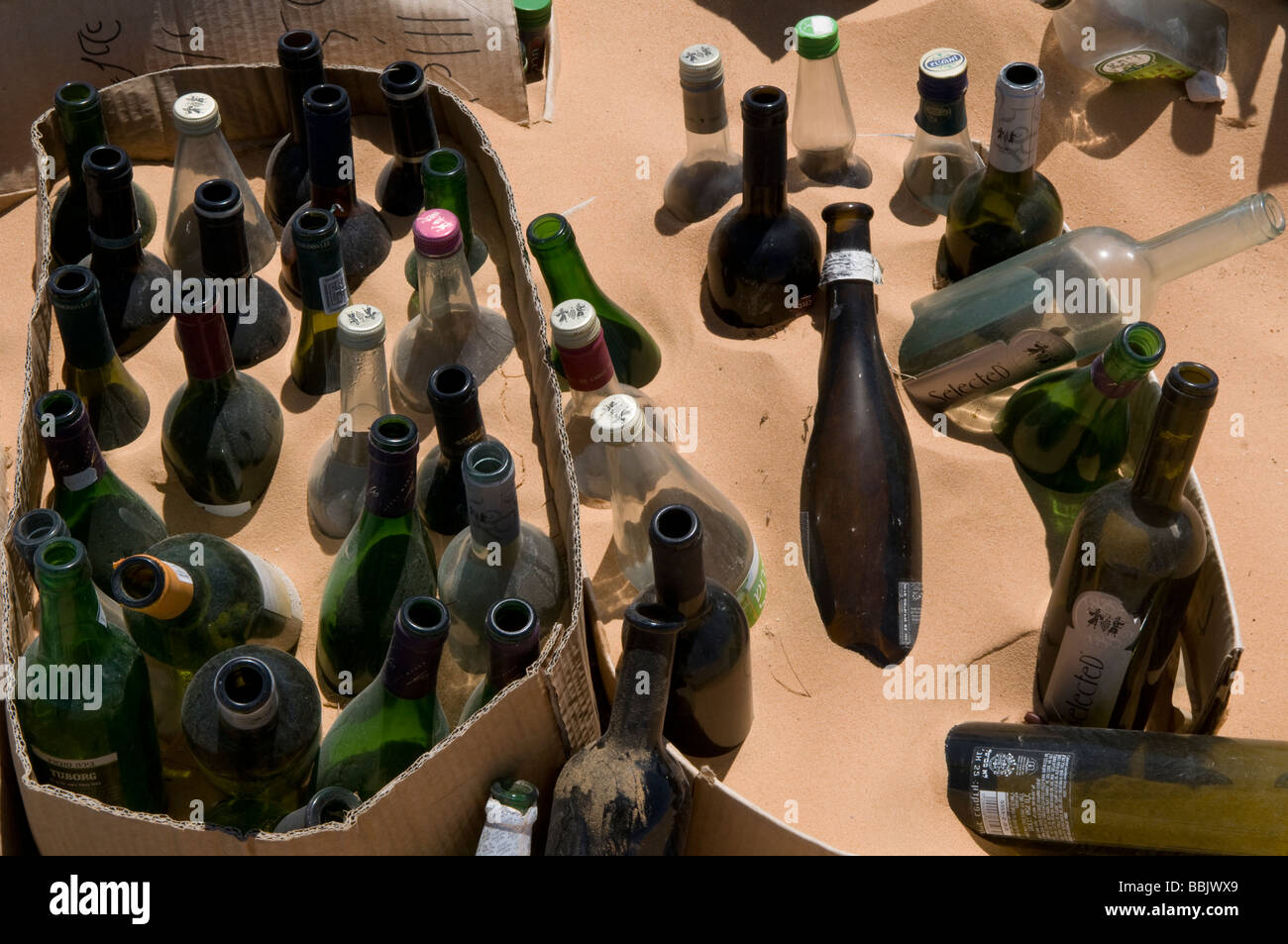 Stack of empty bottles in the sand Stock Photo - Alamy