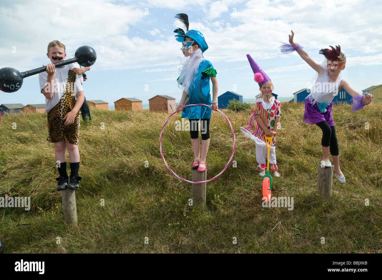 Four children in circus costumes pose on posts or unicycle, Hayling ...
