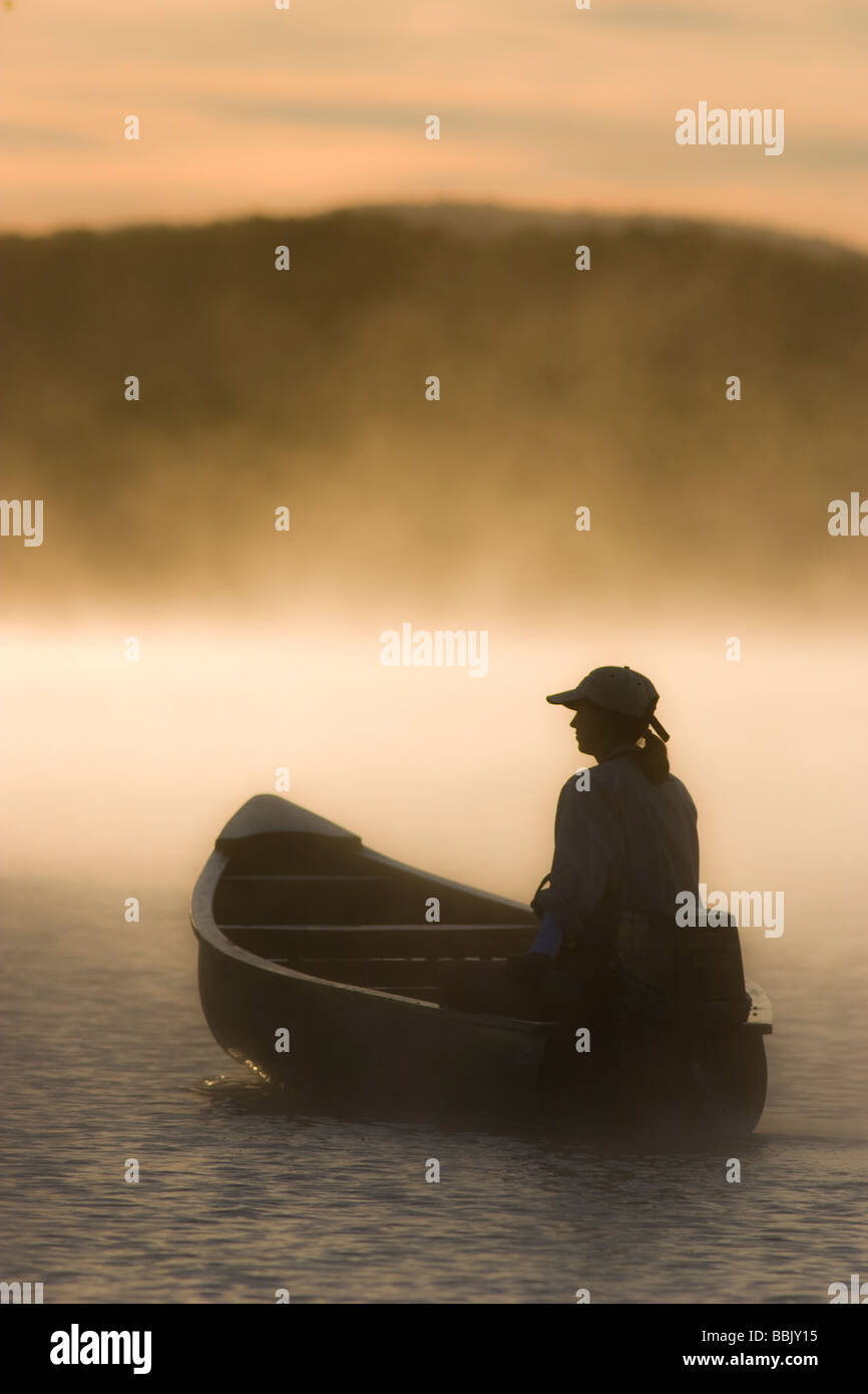 Guide running canoe on a misty lake Stock Photo - Alamy