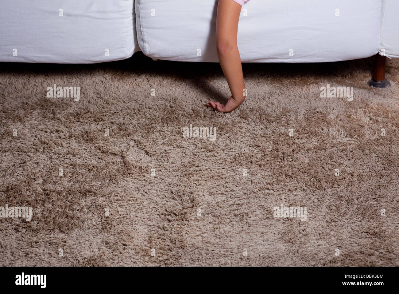 CHILD'S ARM HANGING FROM A SOFA OVER A CARPET Stock Photo - Alamy