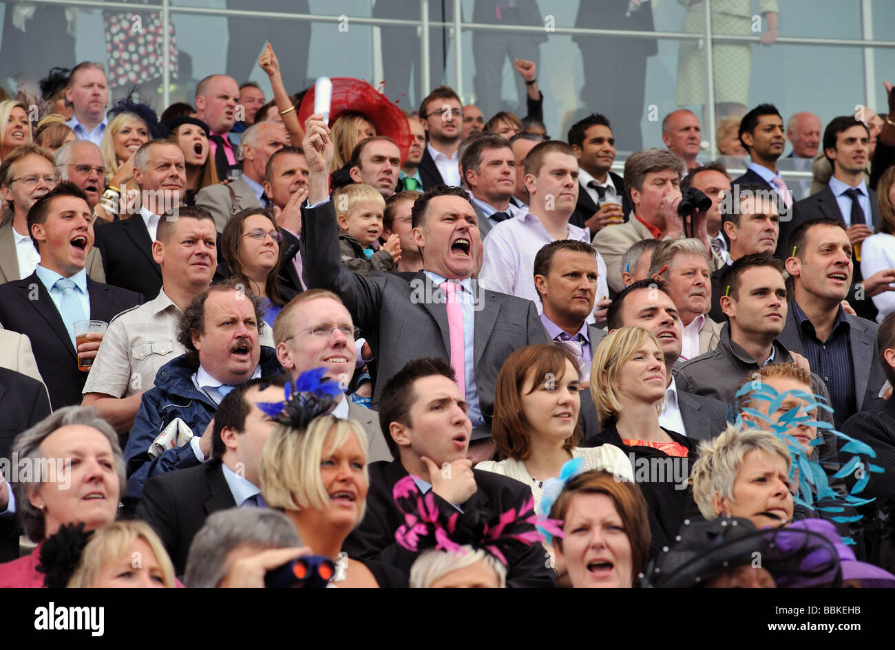 A suited race- goer in a crowd cheering on his winning horse at Epsom ...