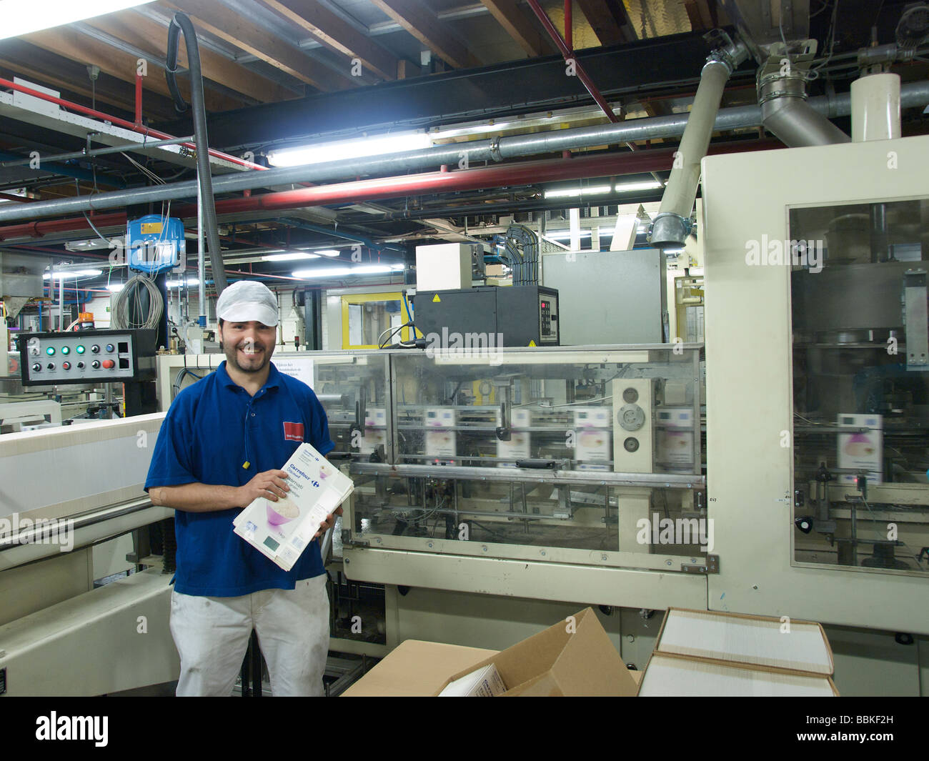 Smiling industry worker at packaging machine in rice factory ...