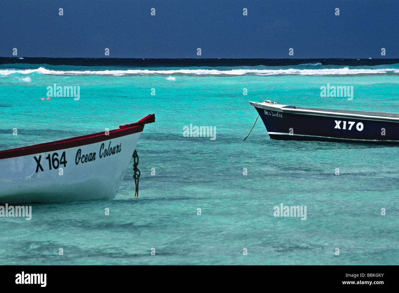 Two small boats at anchor bow to bow waves breaking in distance, St ...