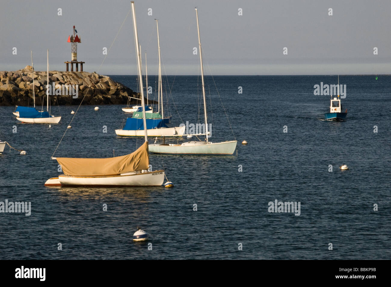 Sailboats in Rockport Outer Harbor in the evening. Two people on jetty ...