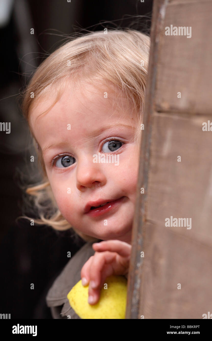 Portrait of a little girl curiously looking around a corner Stock Photo ...