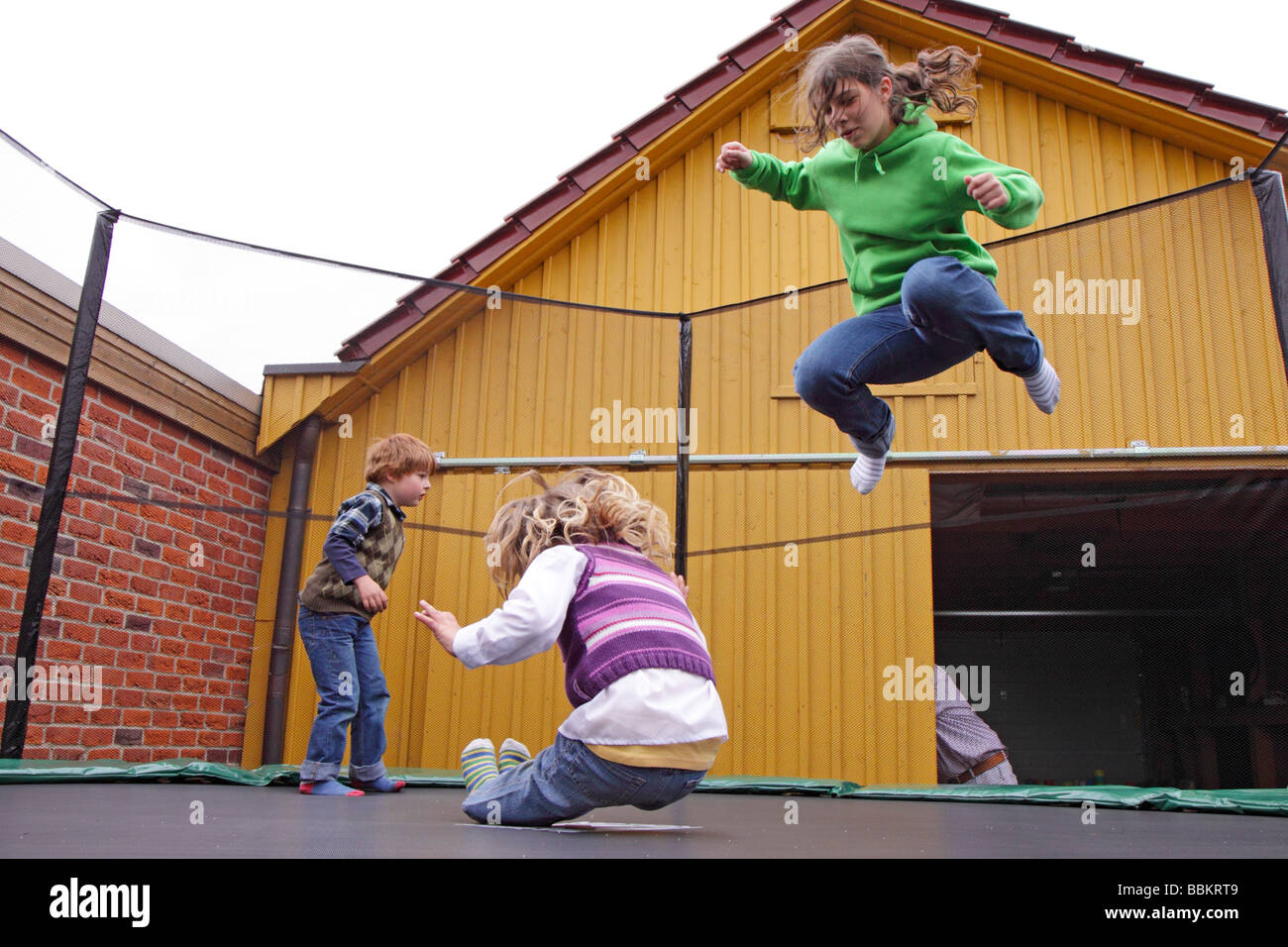 three children jumping on a trampoline Stock Photo - Alamy
