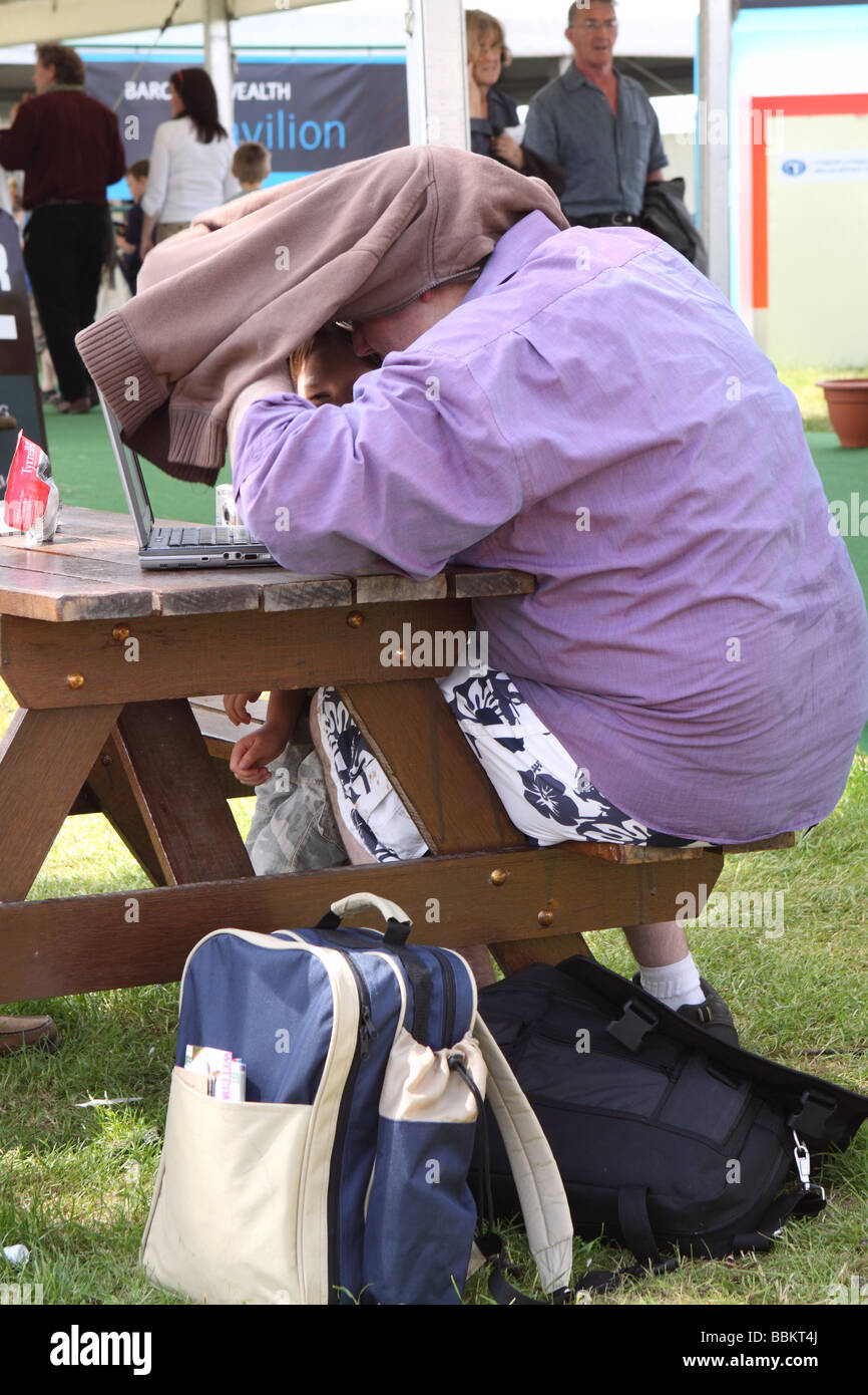 Man struggling to view images on a laptop computer outside on a sunny ...