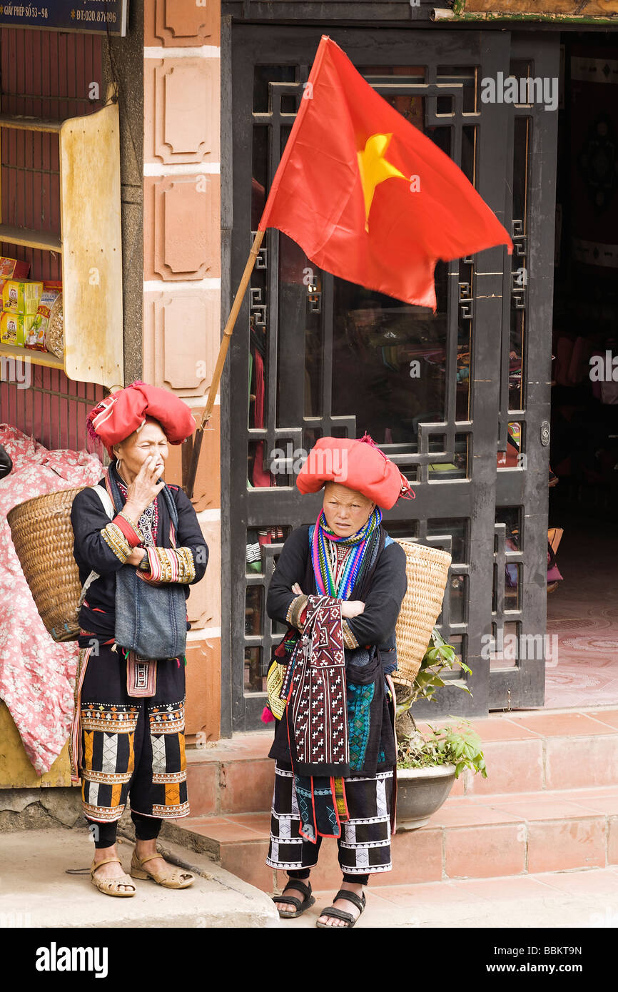 Two Red Dzao women under a Vietnamese flag on Cau May Street in Sapa ...