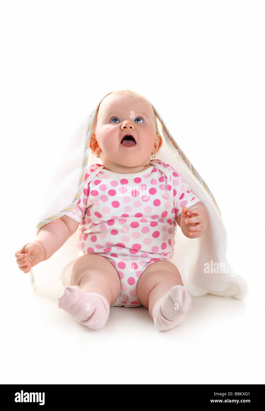 Cute baby looking up in excitement sitting under white blanket isolated ...