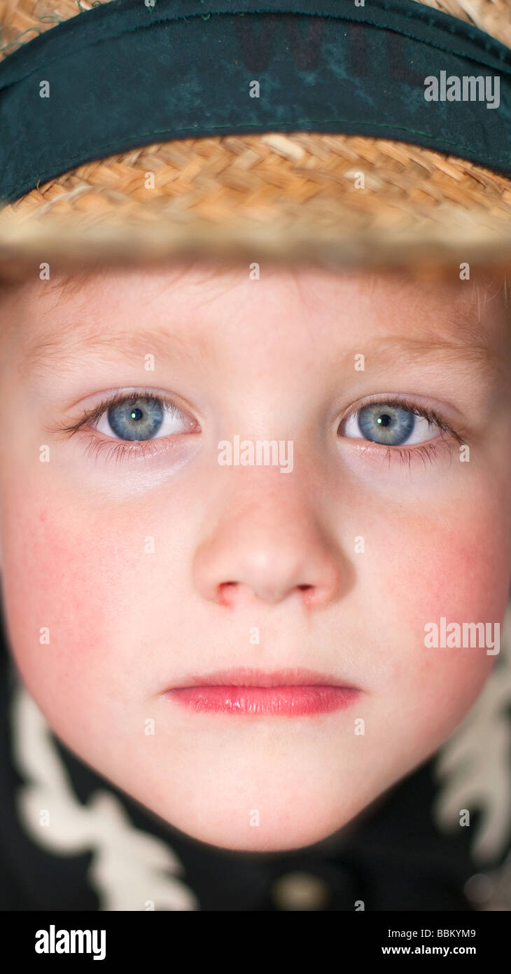 Young boy with a cowboy hat looking up into the camera with a serious ...