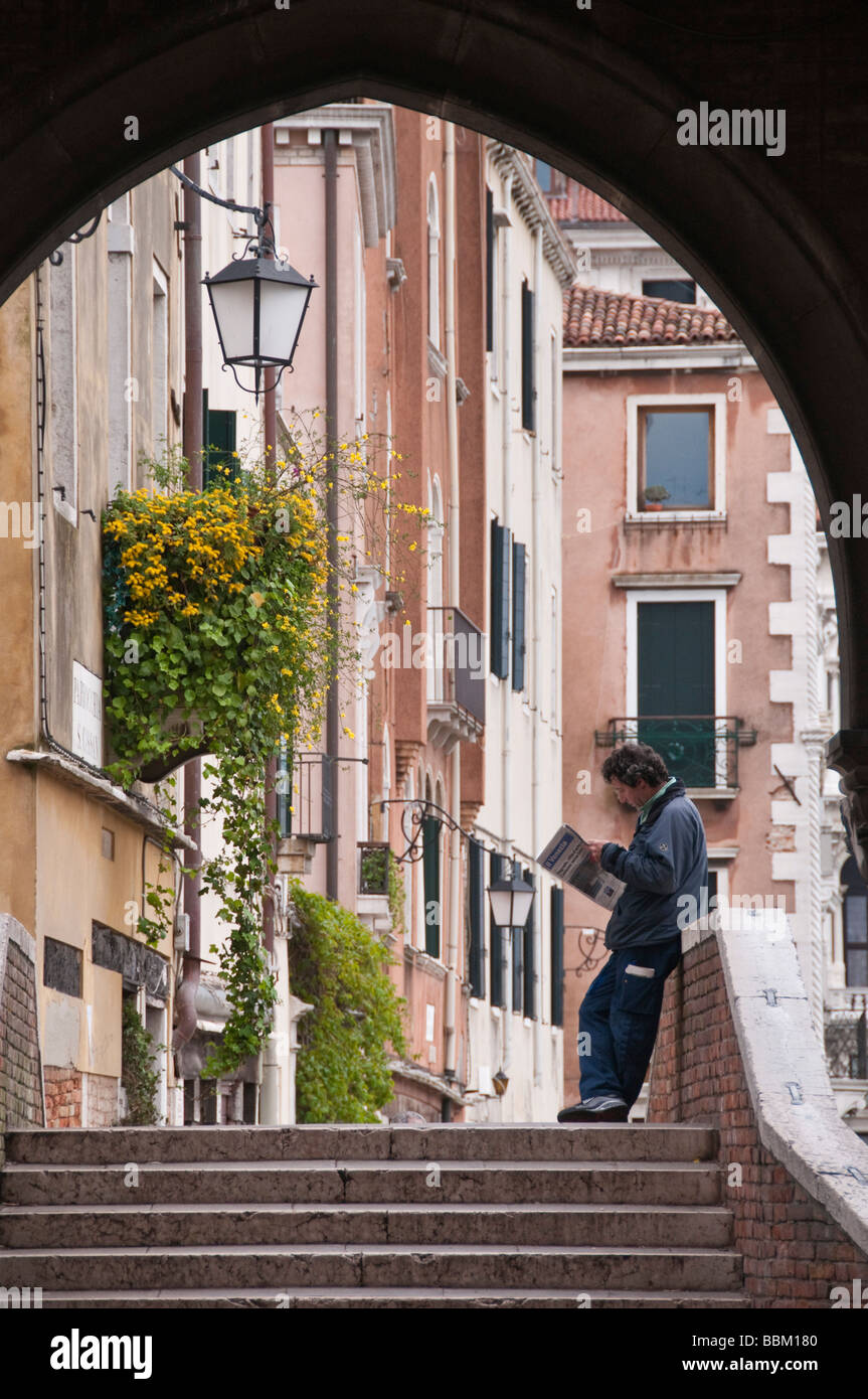 Man reading morning newspaper on canal bridge San Polo Venice Italy ...