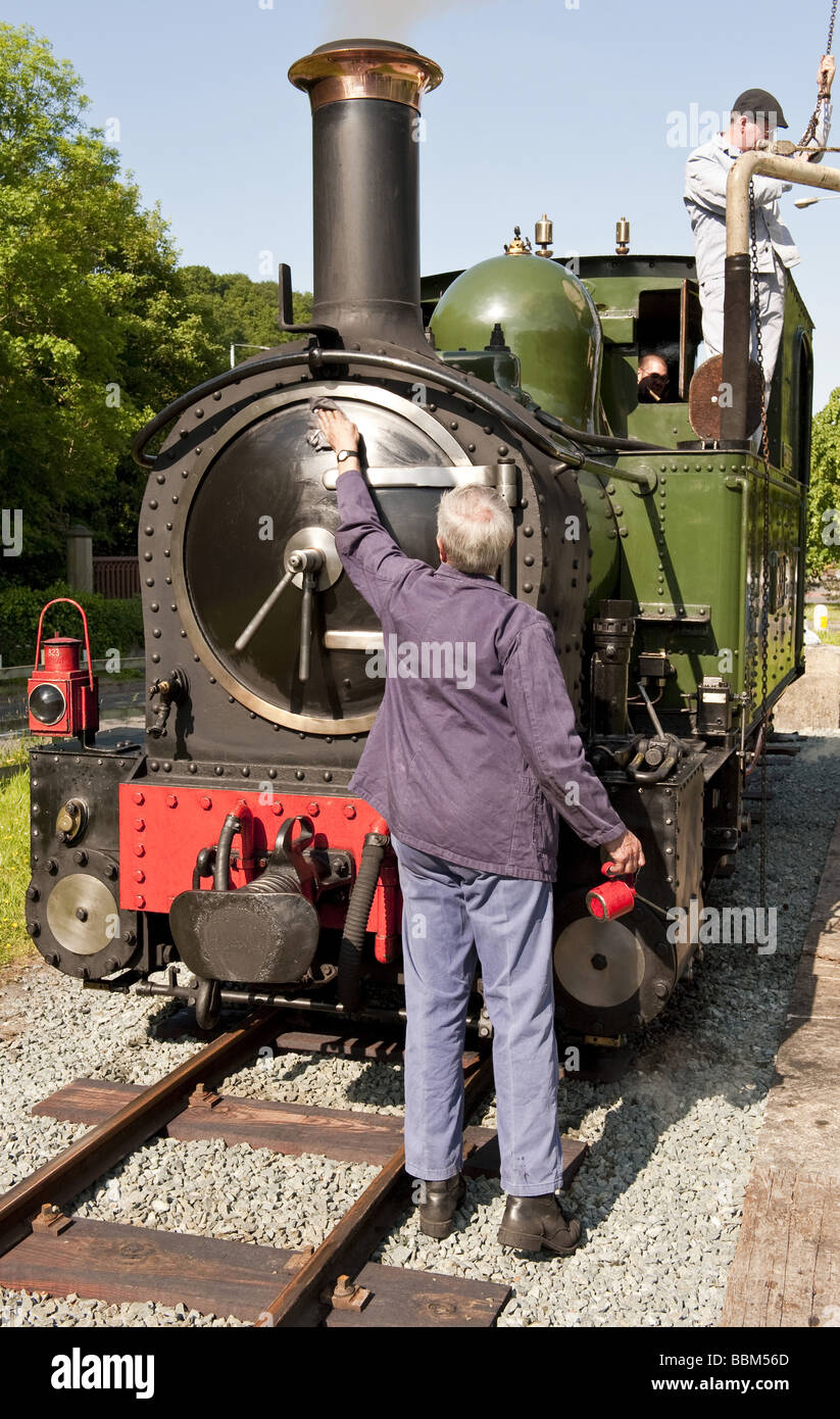 Train driver and engineer refill water and lubricate steam engine with ...