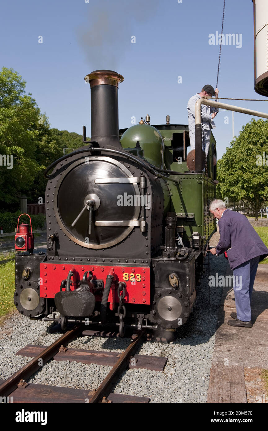Train driver and engineer refill water and lubricate steam engine with ...