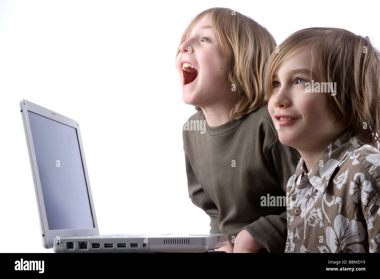 Two boys laughing in front of a laptop Stock Photo - Alamy