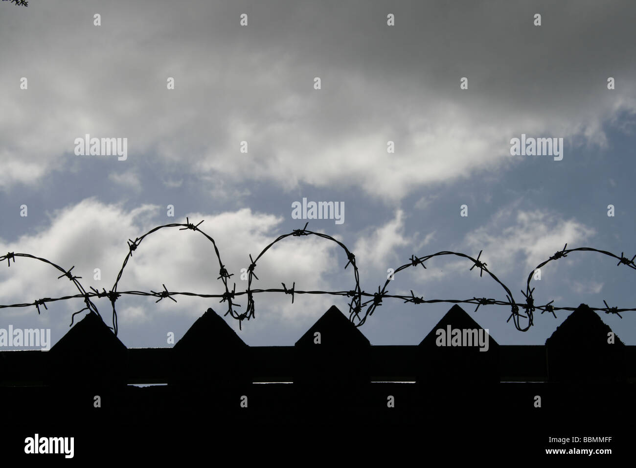dark high wall fence with barbed wire outdoors Stock Photo - Alamy