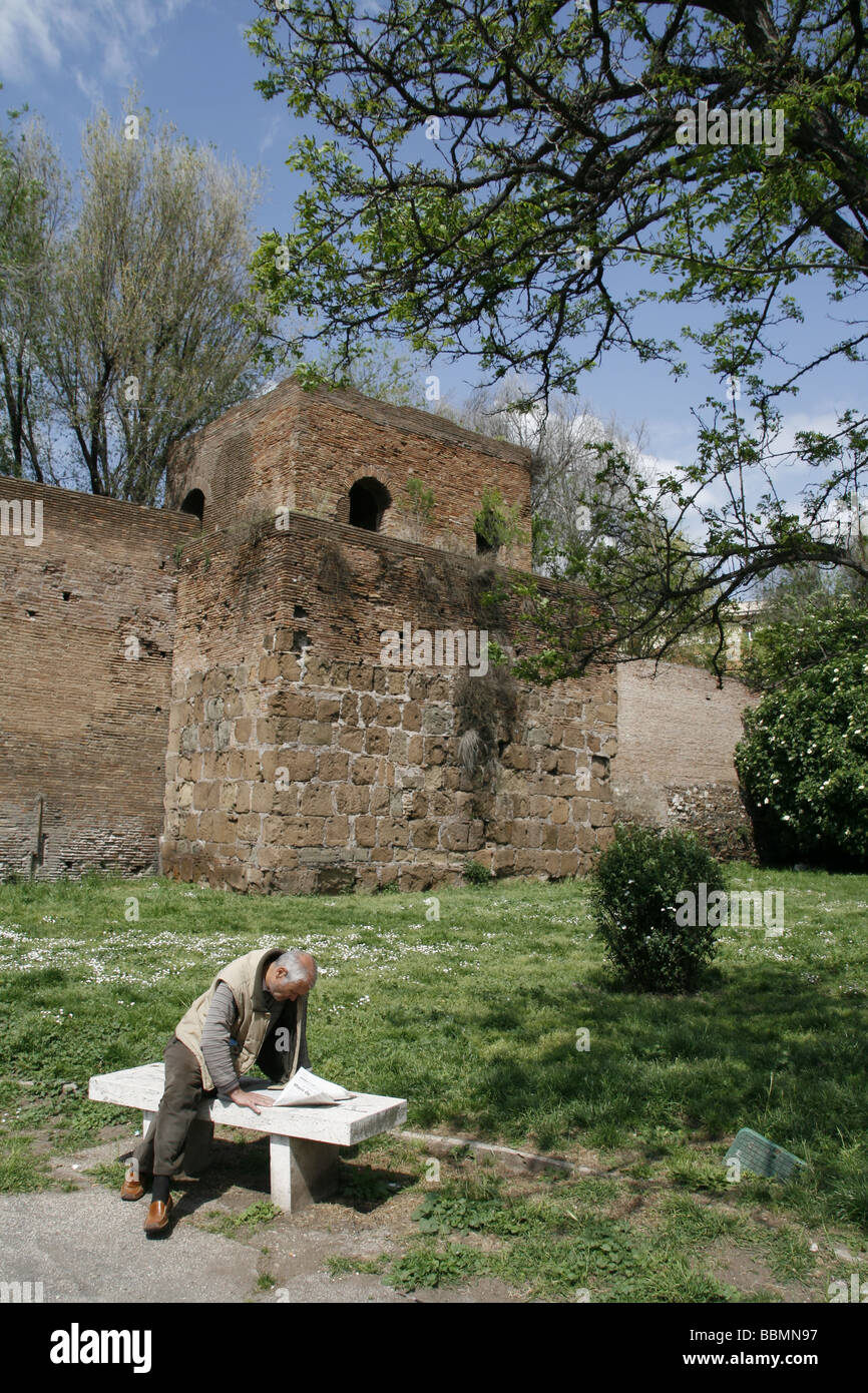 old man reading newspaper by the roman aurelian defence wall in rome ...