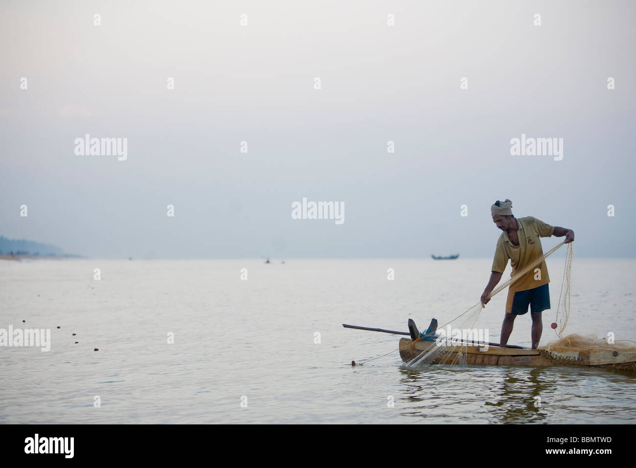 Indian subsistence fisherman pulling in his nets from hand-made wooden ...