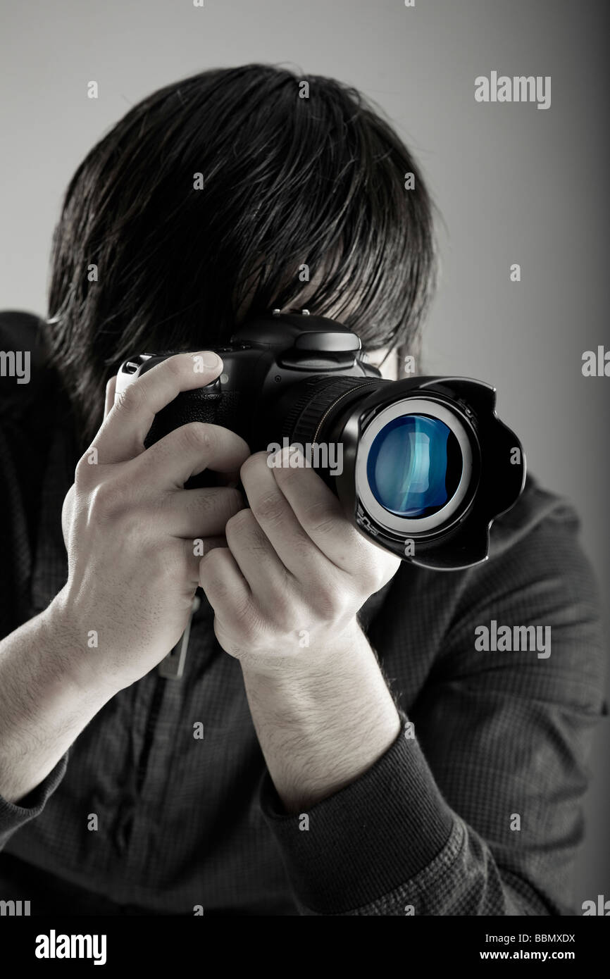 Young man holding a professional DSLR camera and taking pictures Stock ...