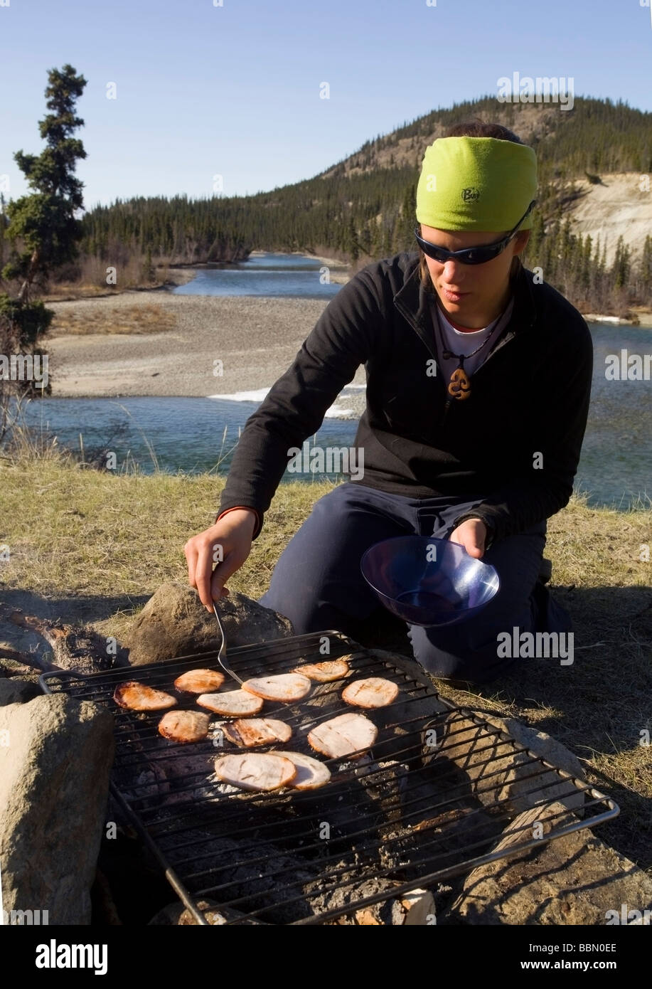Young woman cooking on a camp fire, roasting ham, barbecue, camping ...