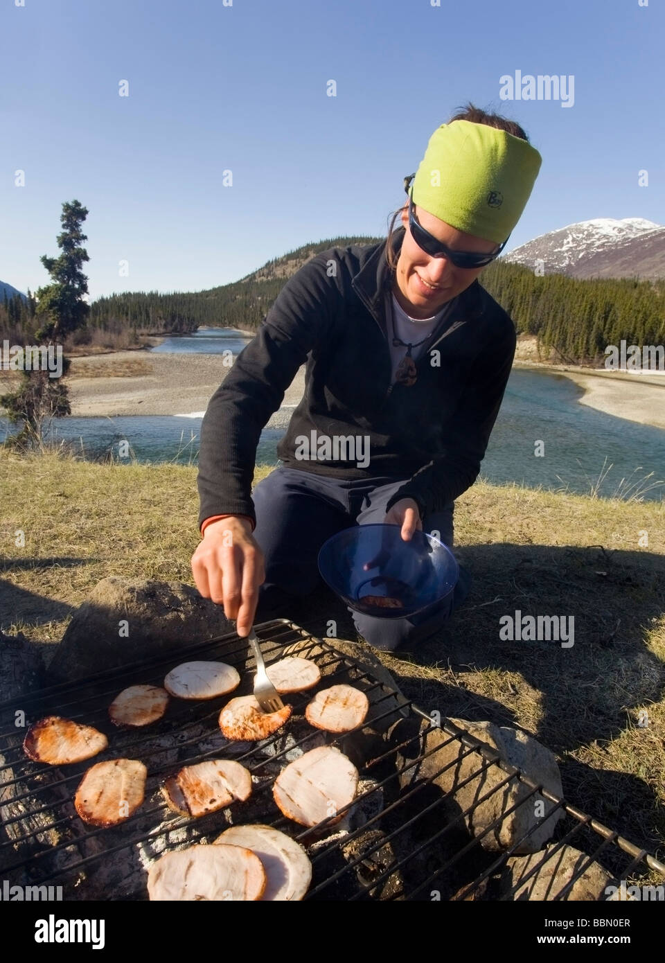 Young woman cooking on a camp fire, roasting ham, barbecue, camping ...