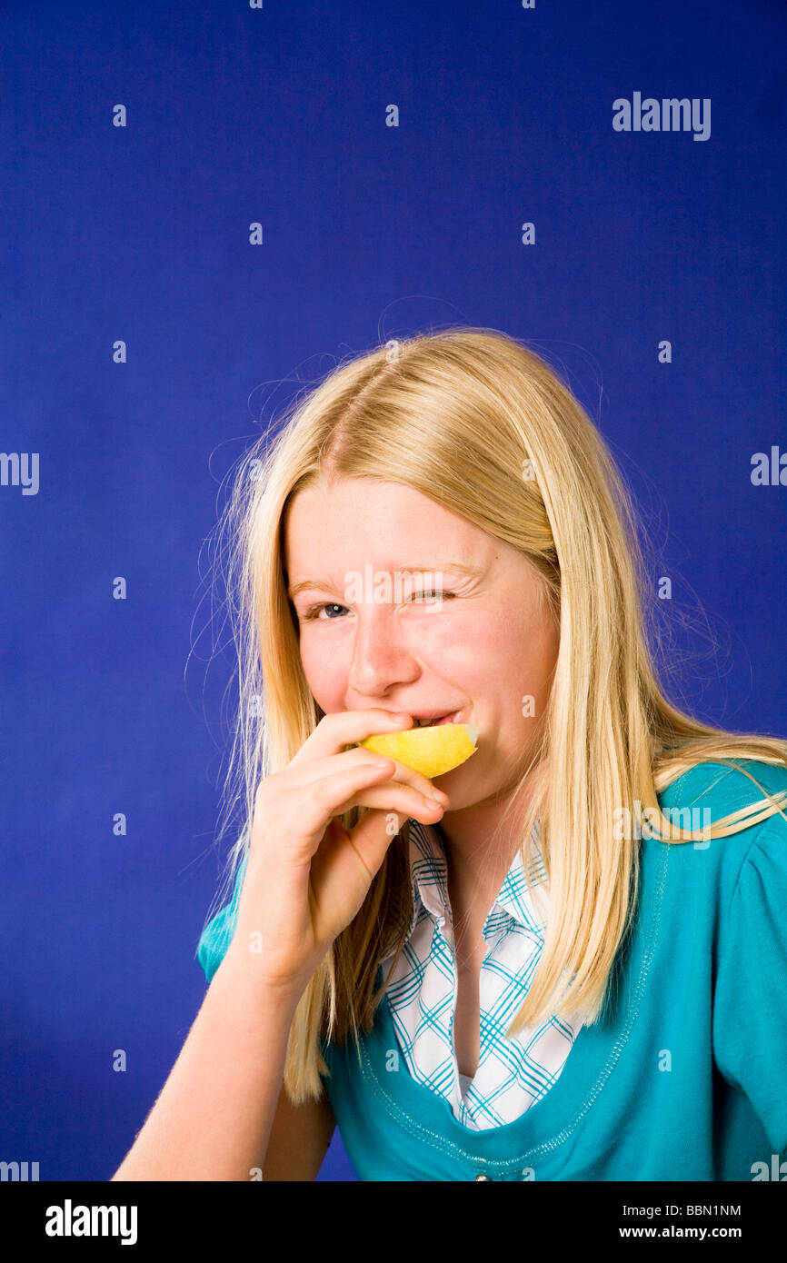 Portrait of young girl eating sour lemon, studio shot cut out MR ...