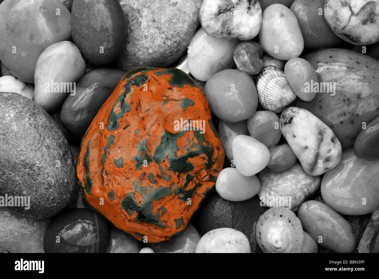 Red brick shaped by seawater in amongst other pebbles and stones Stock ...