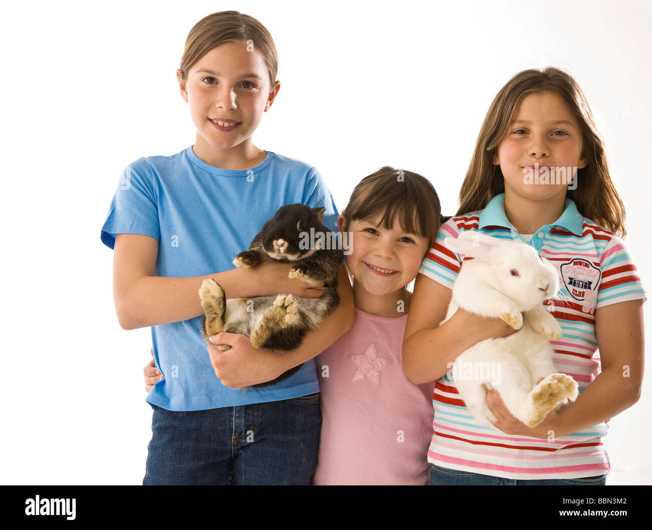 Portrait of three girls, two of them holding a rabbit in their arms ...