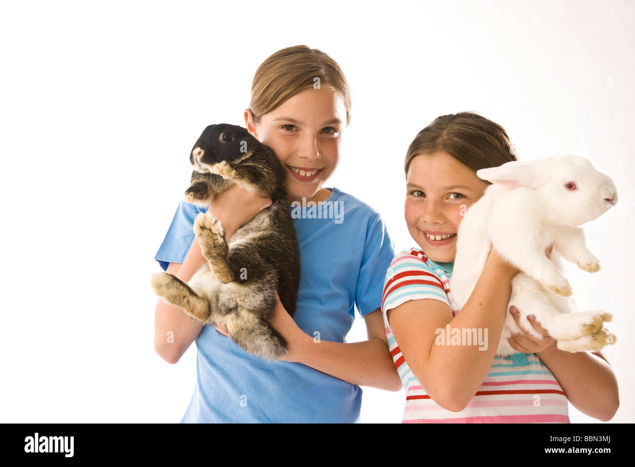 Portrait of two girls laughing, each with a rabbit in her arms Stock ...