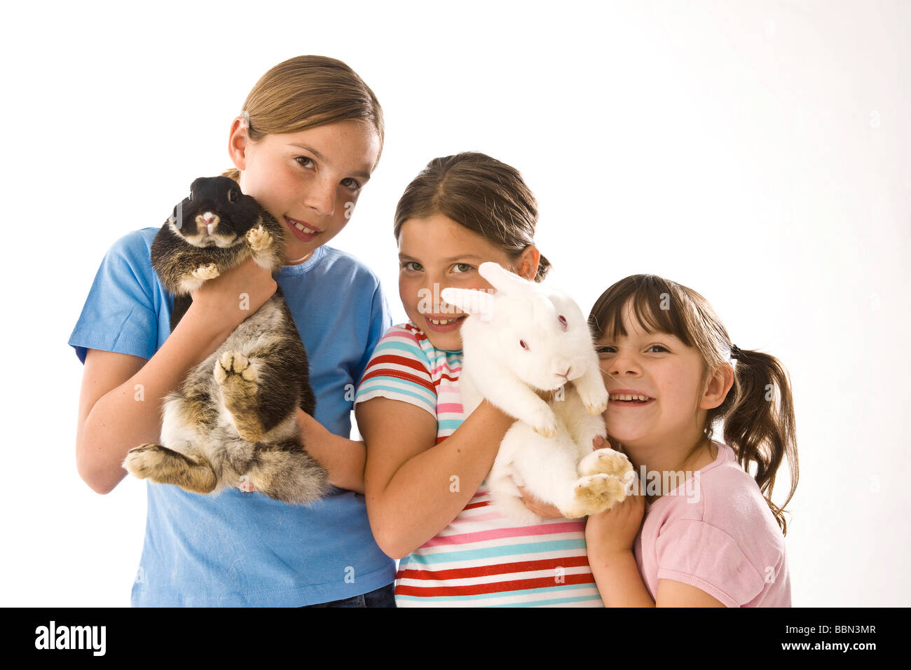 Portrait of three girls, two of them holding a rabbit in their arms ...