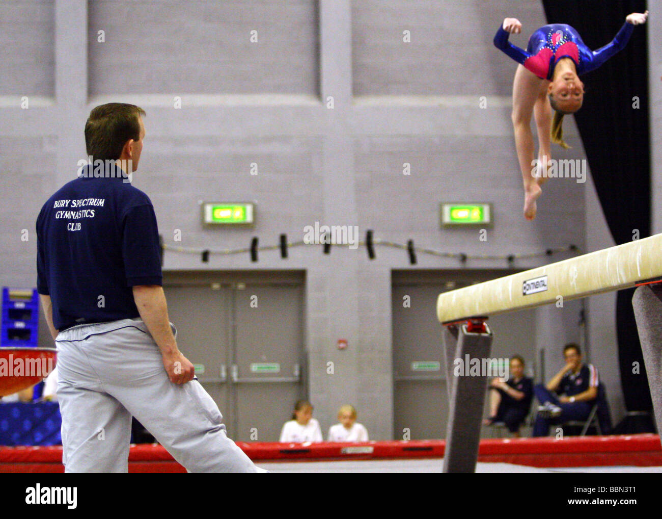 coach watching his gymnast perform on the balance beam in a gymnastics ...