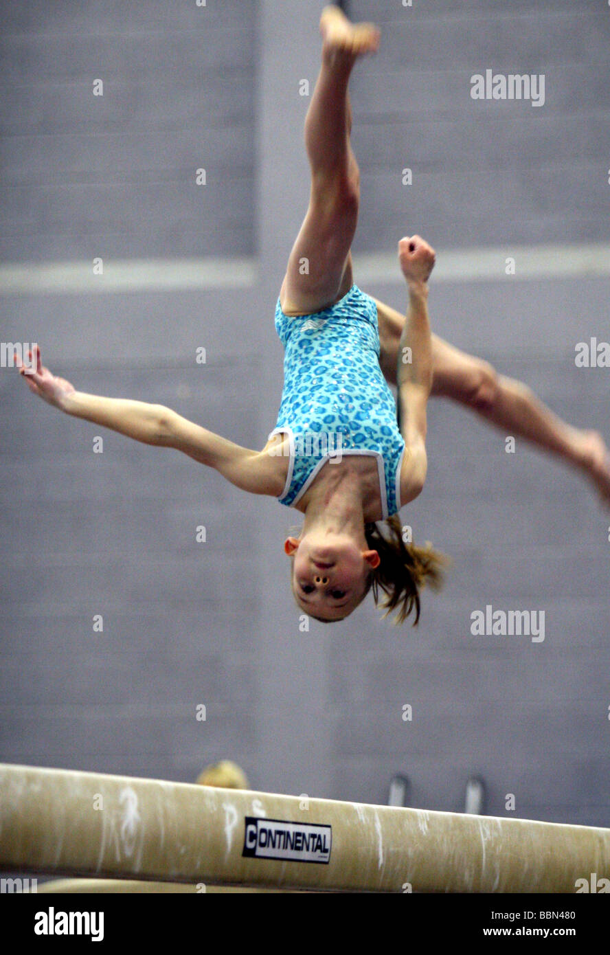gymnast performs backflip on the balance beam aparatus in a gymnastics ...