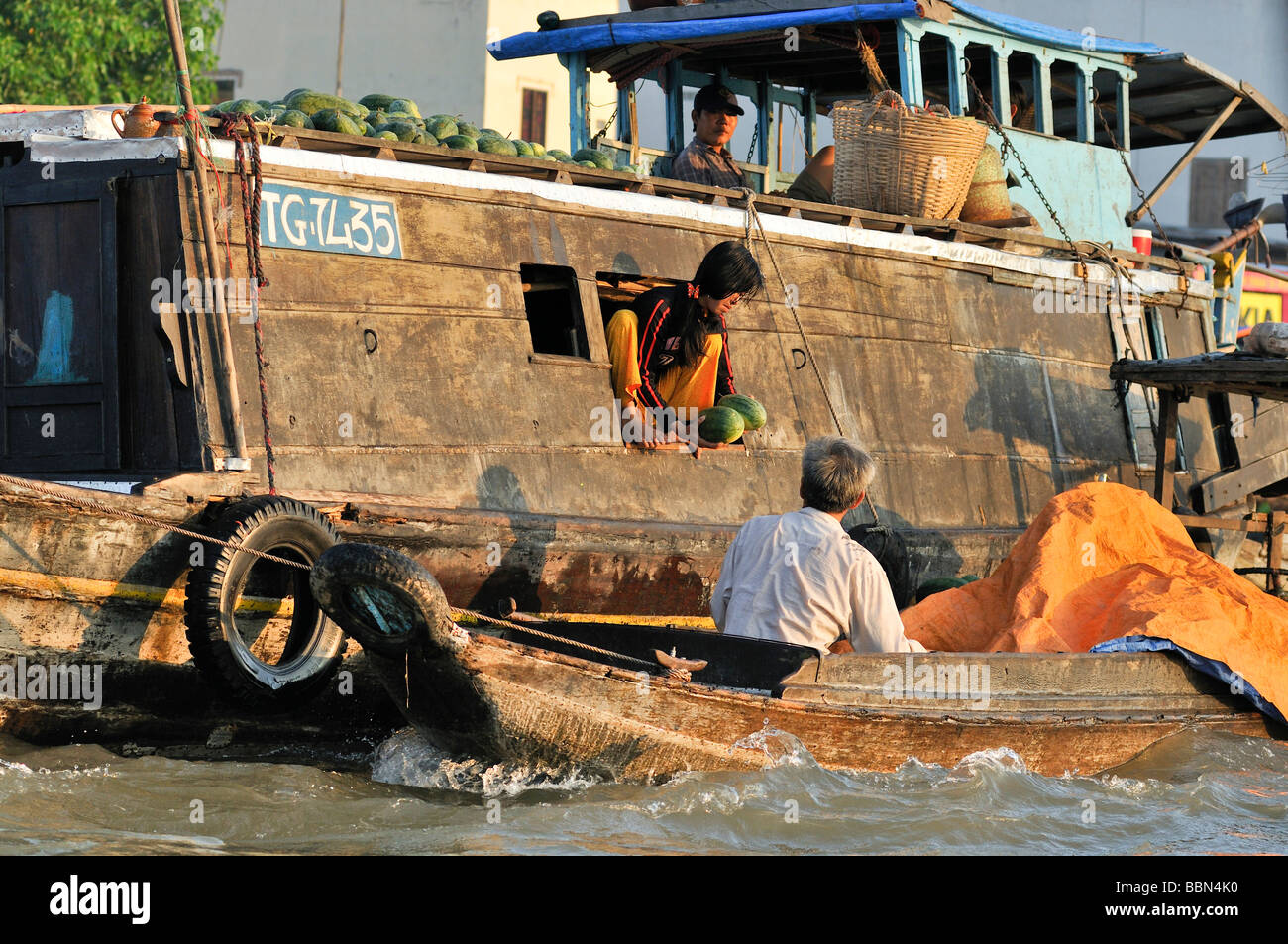 Woman loading fruit, melons, watermelons, from a hatch onto a small ...