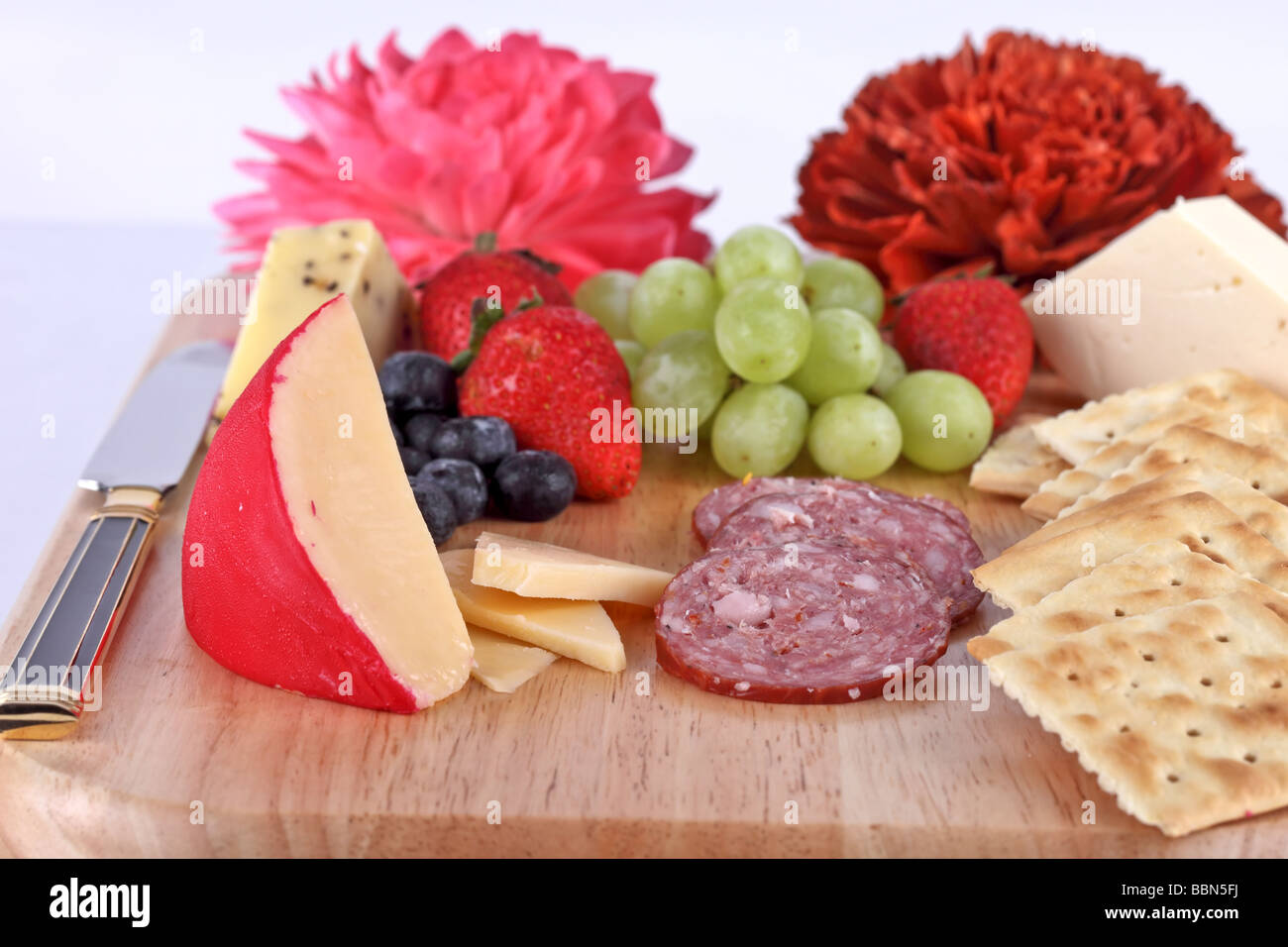 Cheese and salami platter with dry biscuits and fruit on a wooden board ...