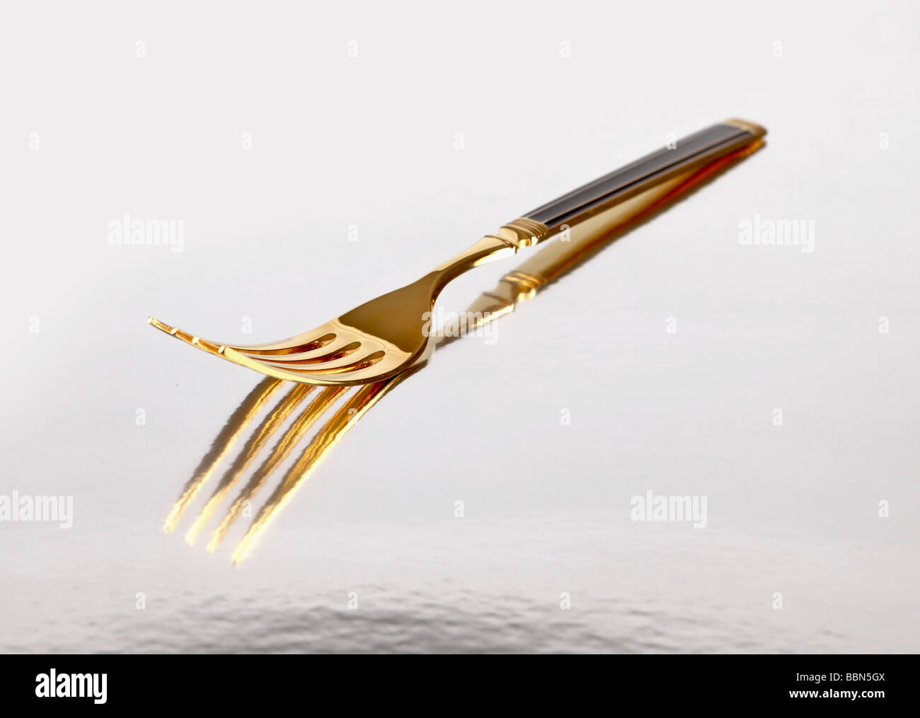 Single golden fork on a reflective background for a simple abstract ...