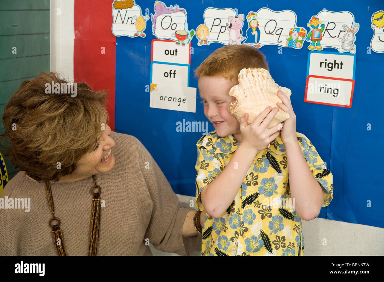 Teacher and kindergarten student holding shell in classroom MR ...