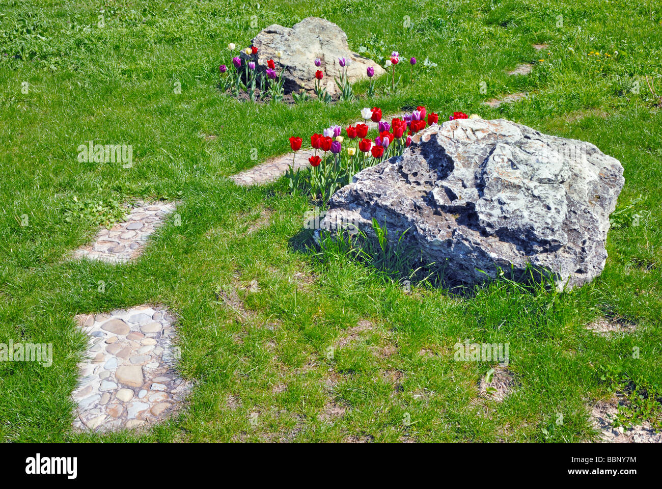 Garden stone path with boulder and flowers Stock Photo - Alamy