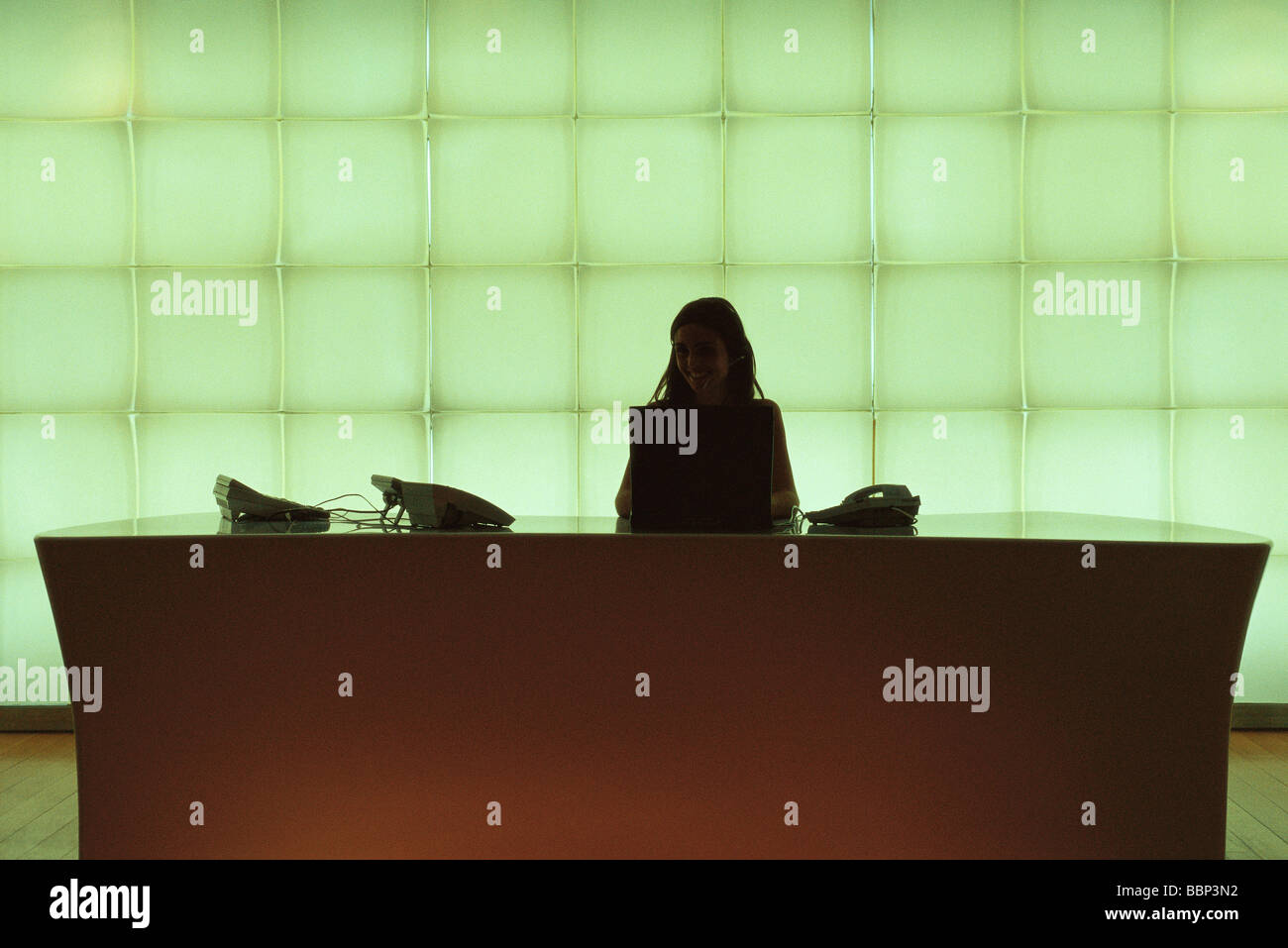 Receptionist at desk smiling at camera Stock Photo - Alamy