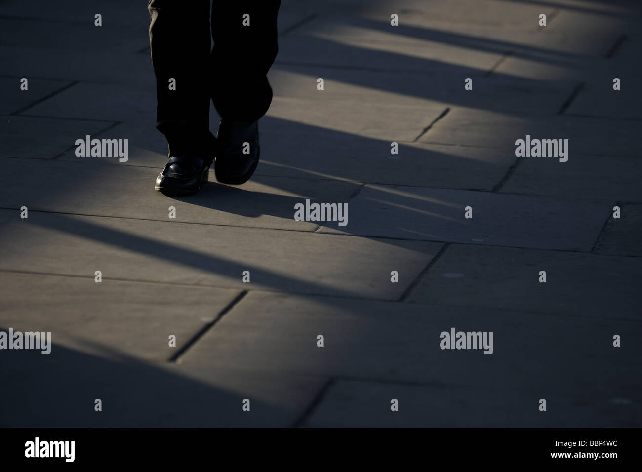 An office worker walks on the pavement with sunlight and shadows Stock ...