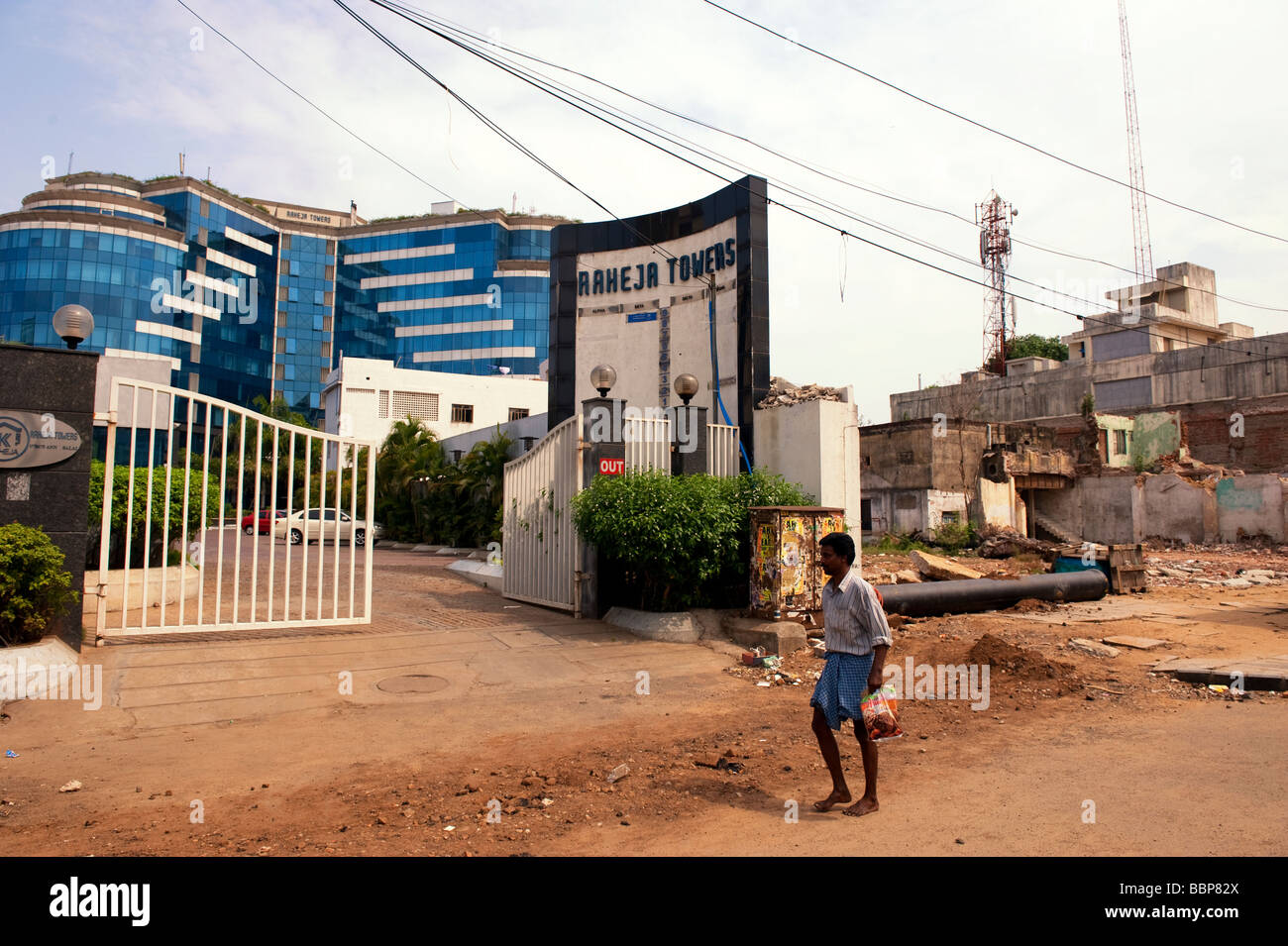 Indian contrasts - barefoot man walks past a modern IT building with ...