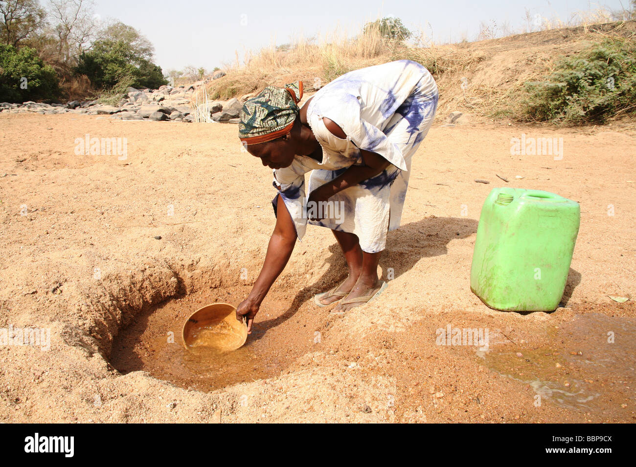 A blind woman collecting water from a dry river bed, Northern Ghana ...